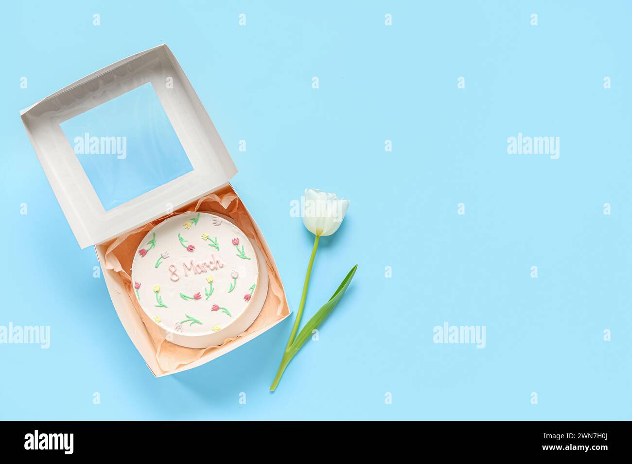 Box with sweet bento cake and beautiful tulip on blue background ...