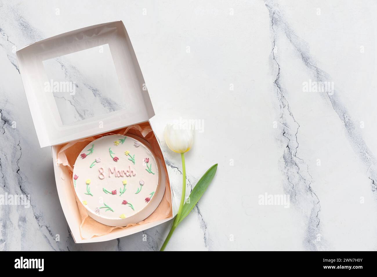 Box with sweet bento cake and beautiful tulip on white background ...
