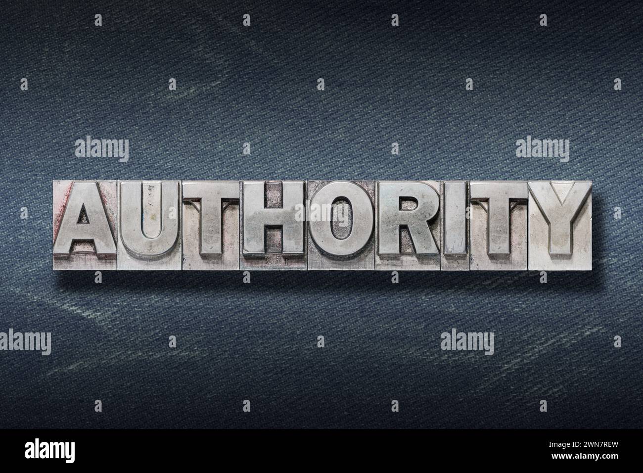authority word made from metallic letterpress on dark jeans background ...