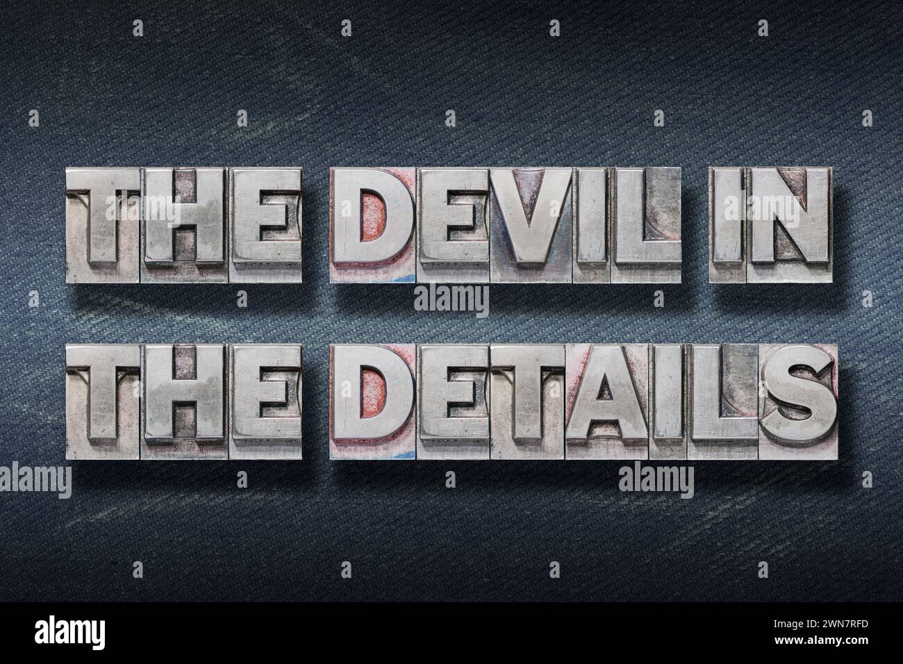the devil in the details phrase made from metallic letterpress on dark jeans background Stock ...