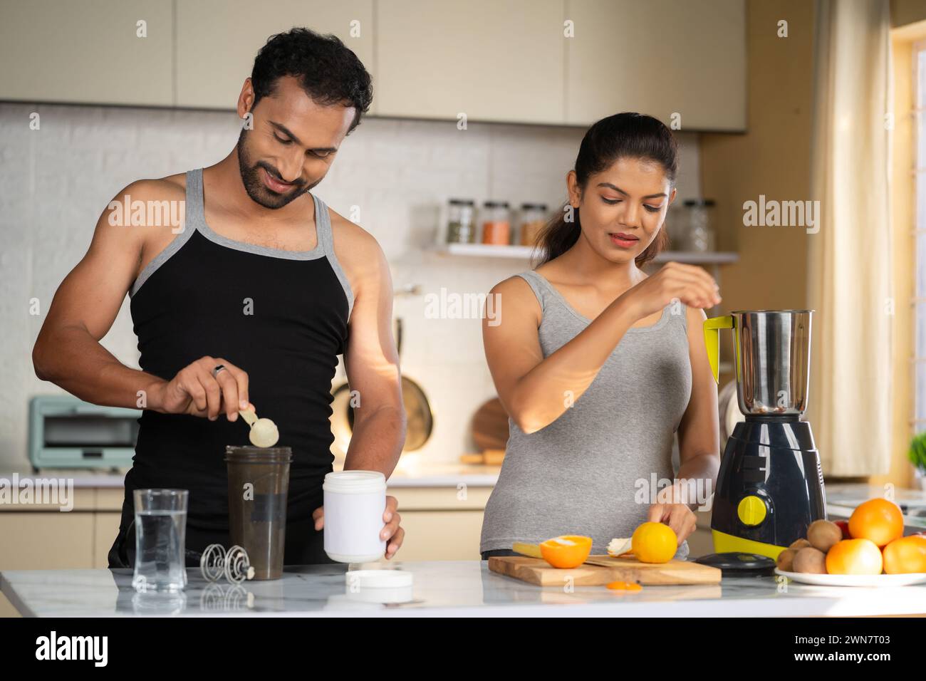 Healthy Indian couple preparing fruit juice and protein shakes after ...
