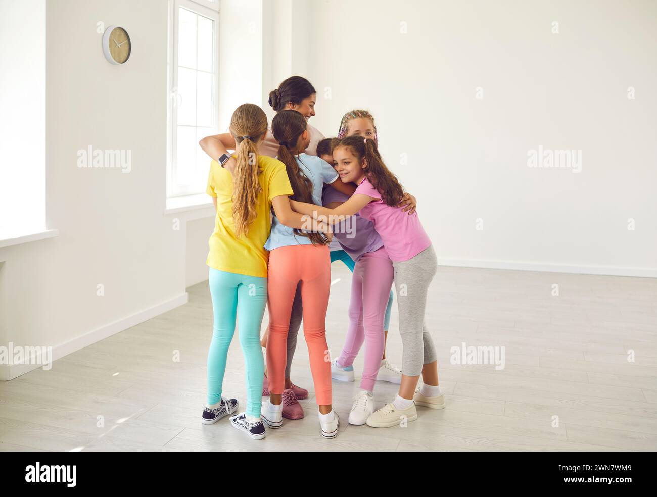Group of happy children hugging their sports trainer or dance teacher ...
