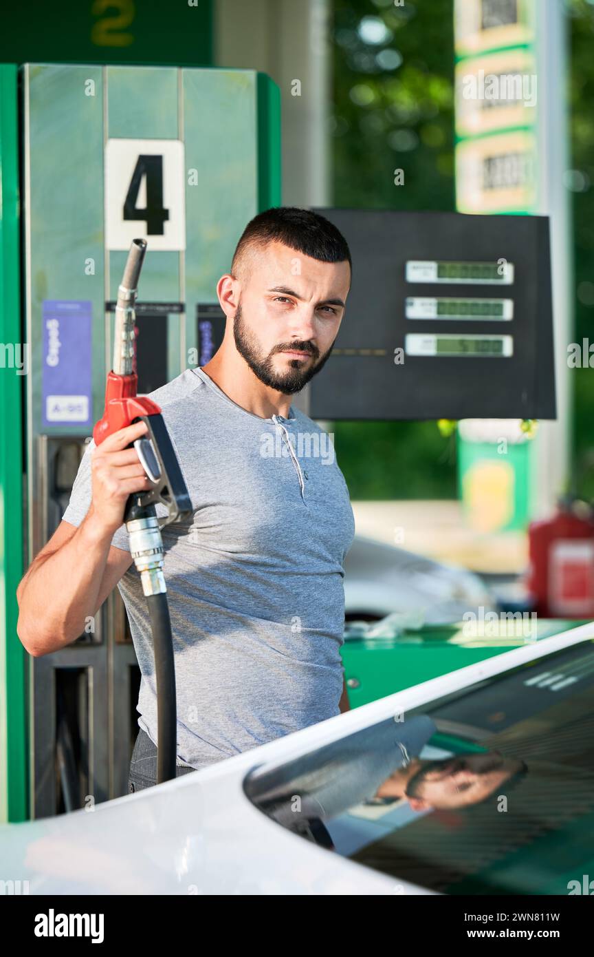 Skilled driver refueling his automobile for long road. Portrait of male ...