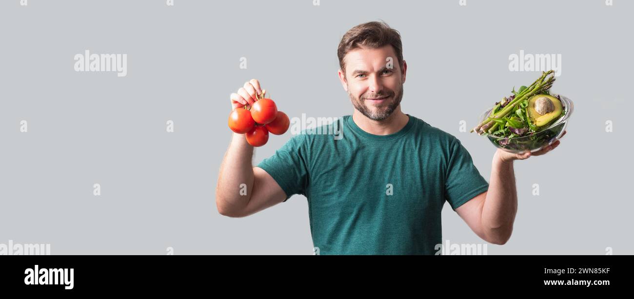 Man hold fresh tomato and vegetable salad isolated on gray background ...