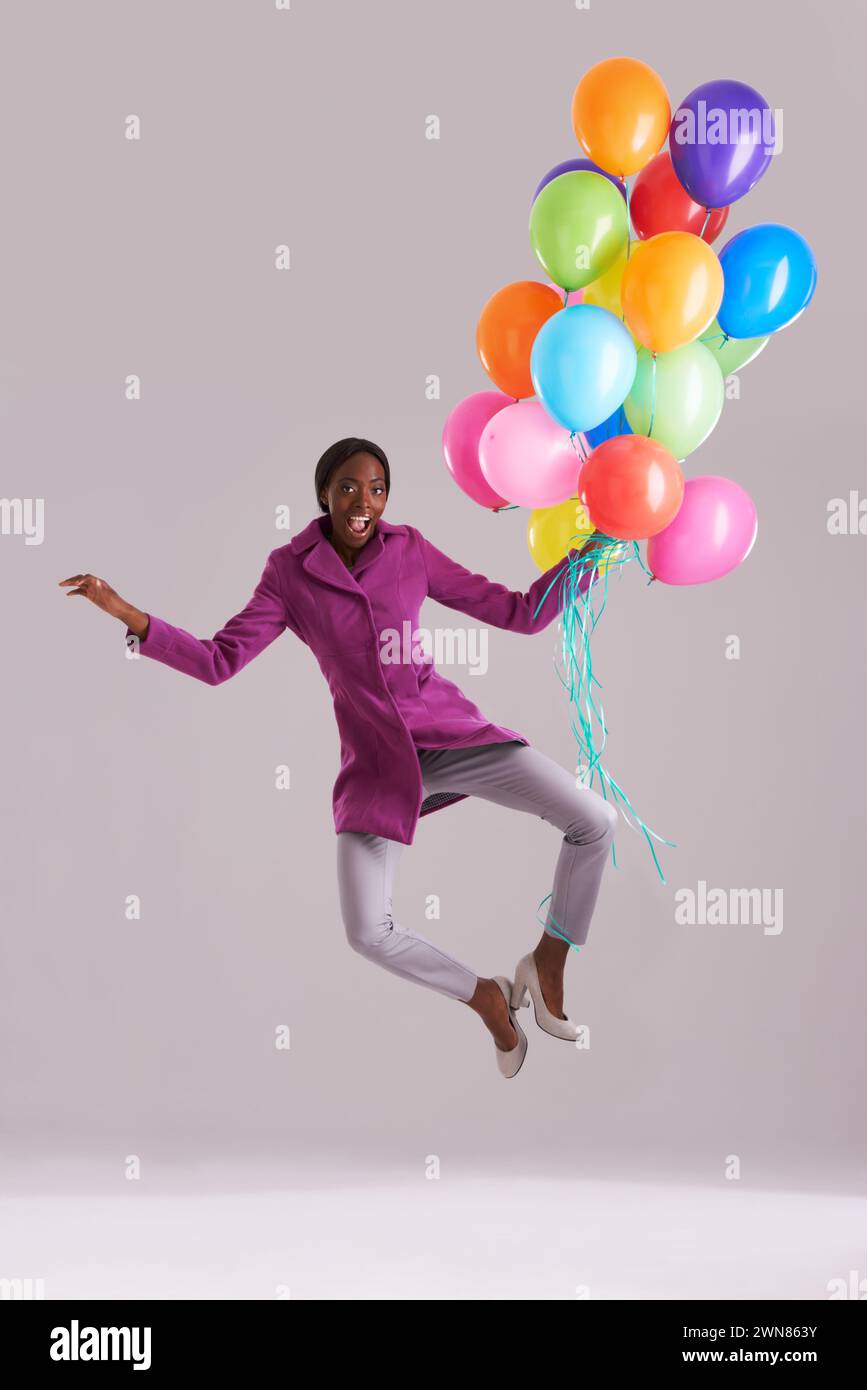 Balloon, jump and portrait of happy black woman in studio for birthday ...