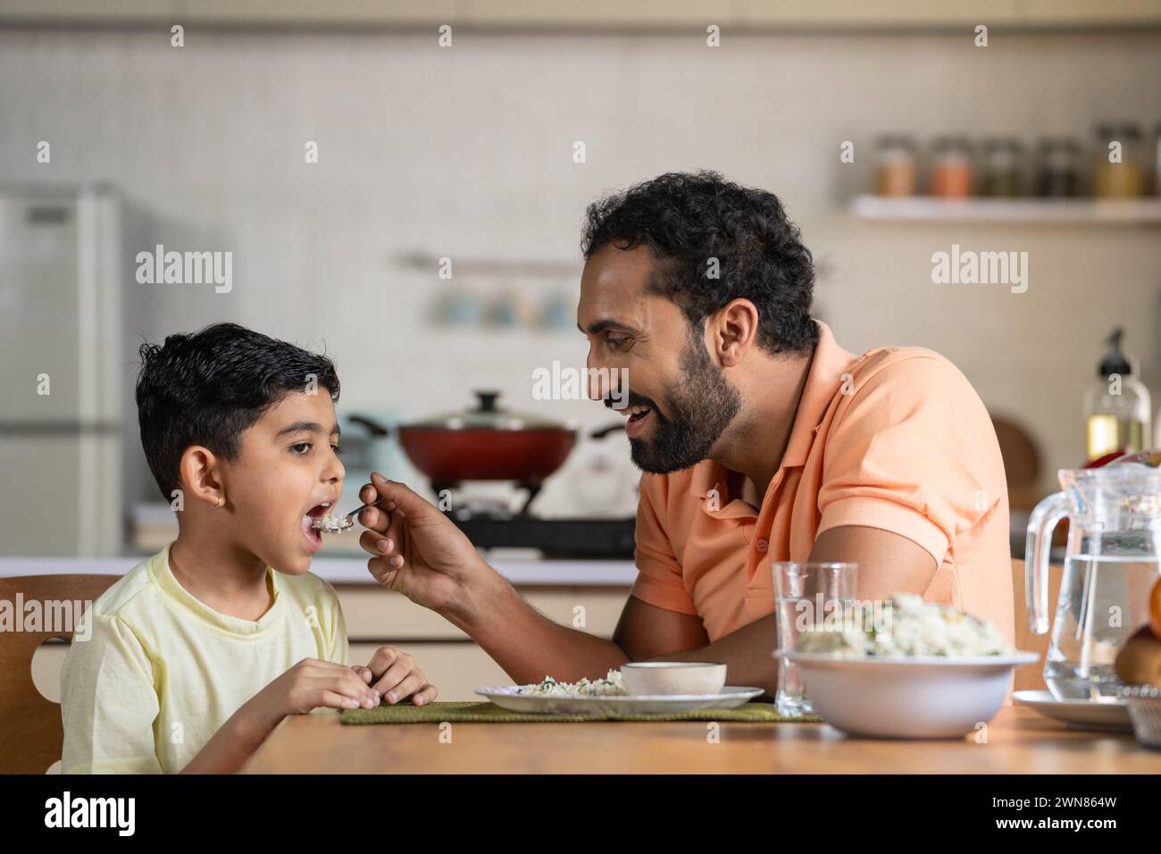 Happy father feeding His child by talking and encouraging at home ...