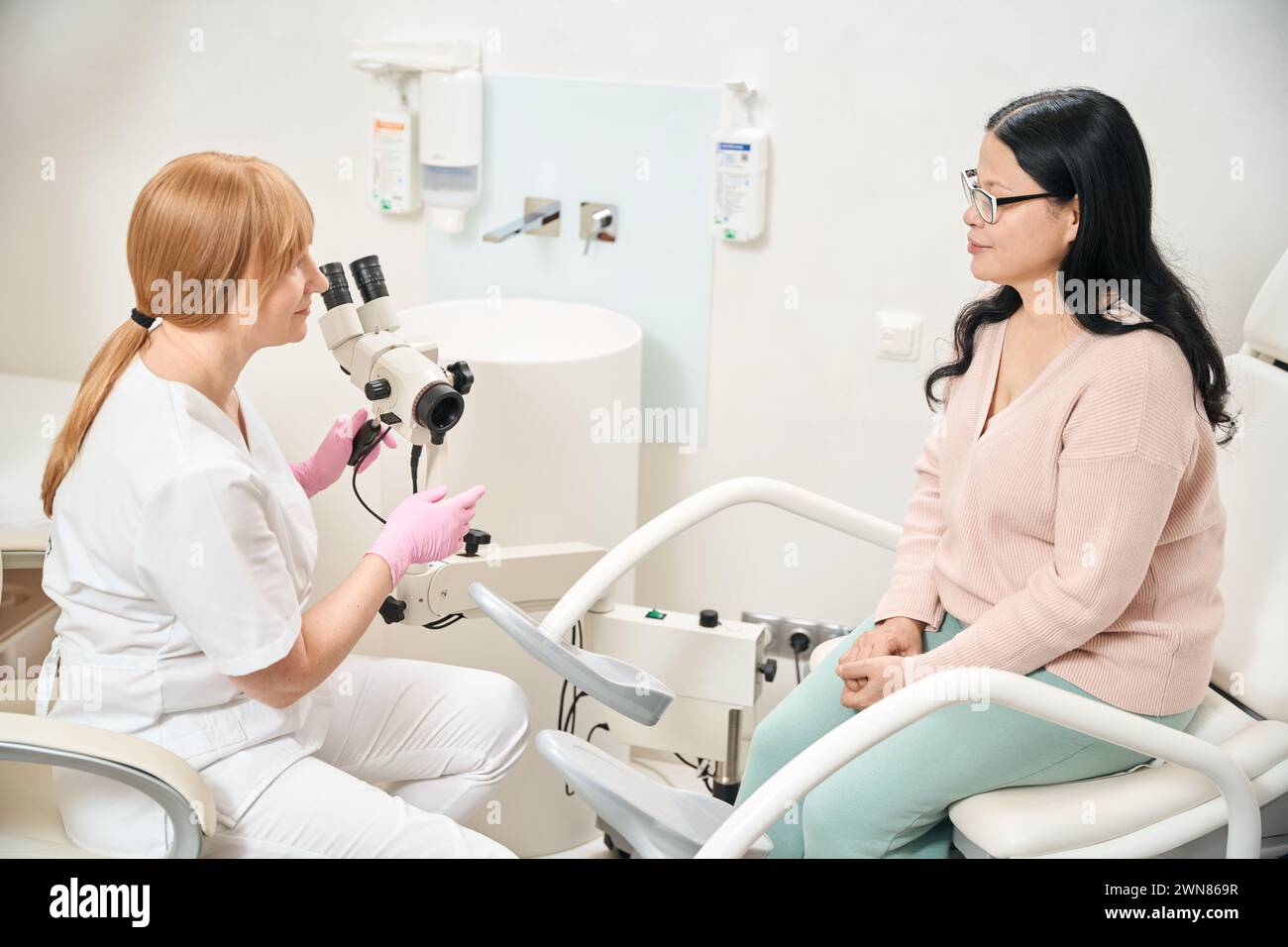 Female gynecologist preparing gynecological microscope to check patient ...