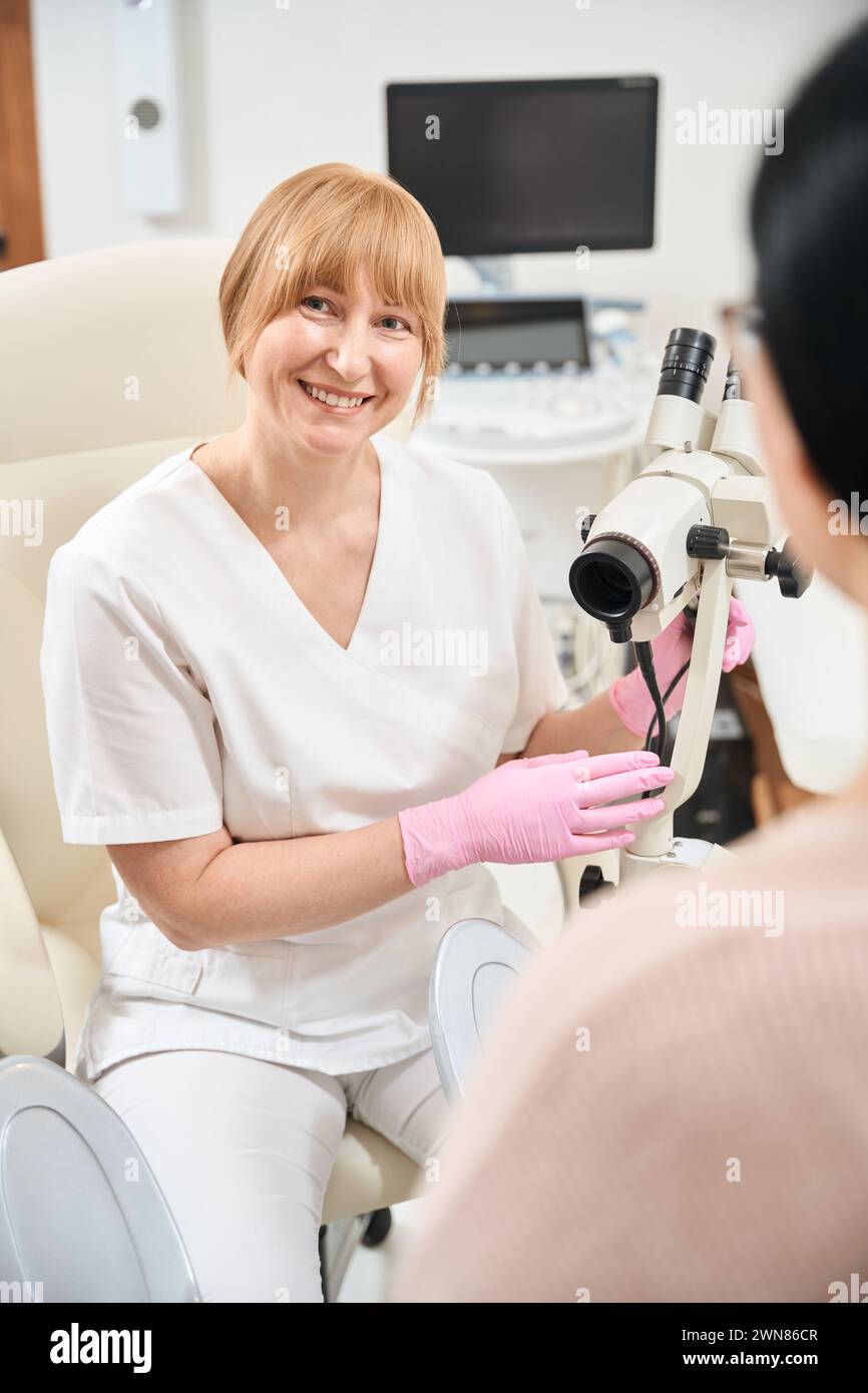 Smiling woman gynecologist showing microscope she use for better pelvic ...