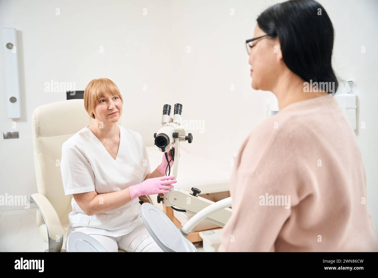 Skilled gynecologist using microscope during pelvic exam for diagnosing ...