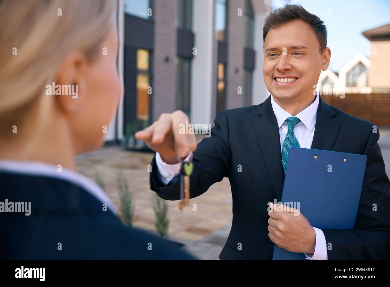 Cheerful estate agent giving keys to female client Stock Photo - Alamy