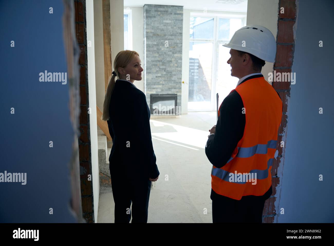 Construction manger and client standing inside house with unfinished ...