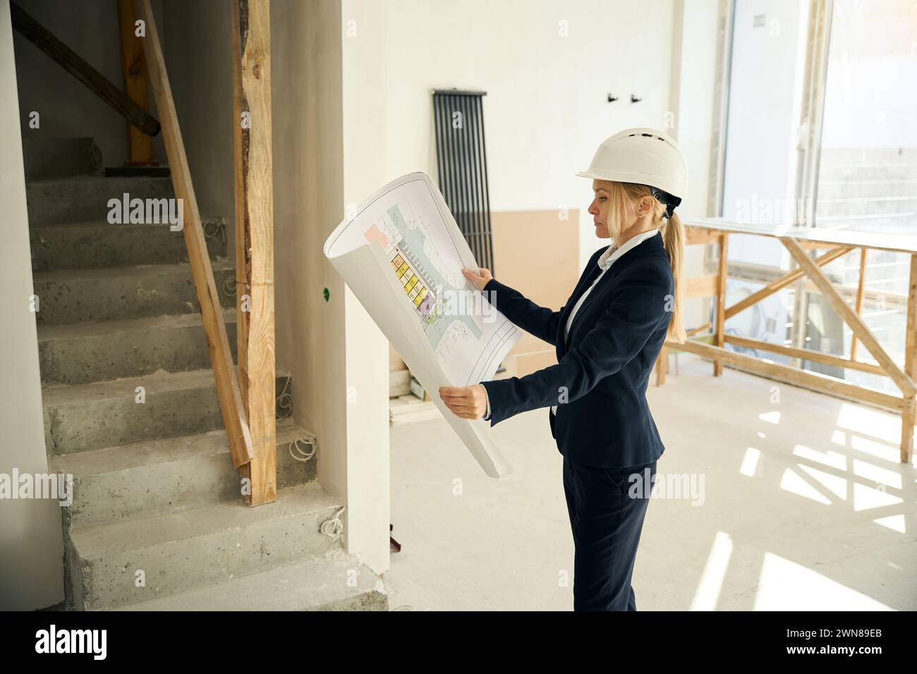Side view photo of female engineer holding plan in hands Stock Photo ...