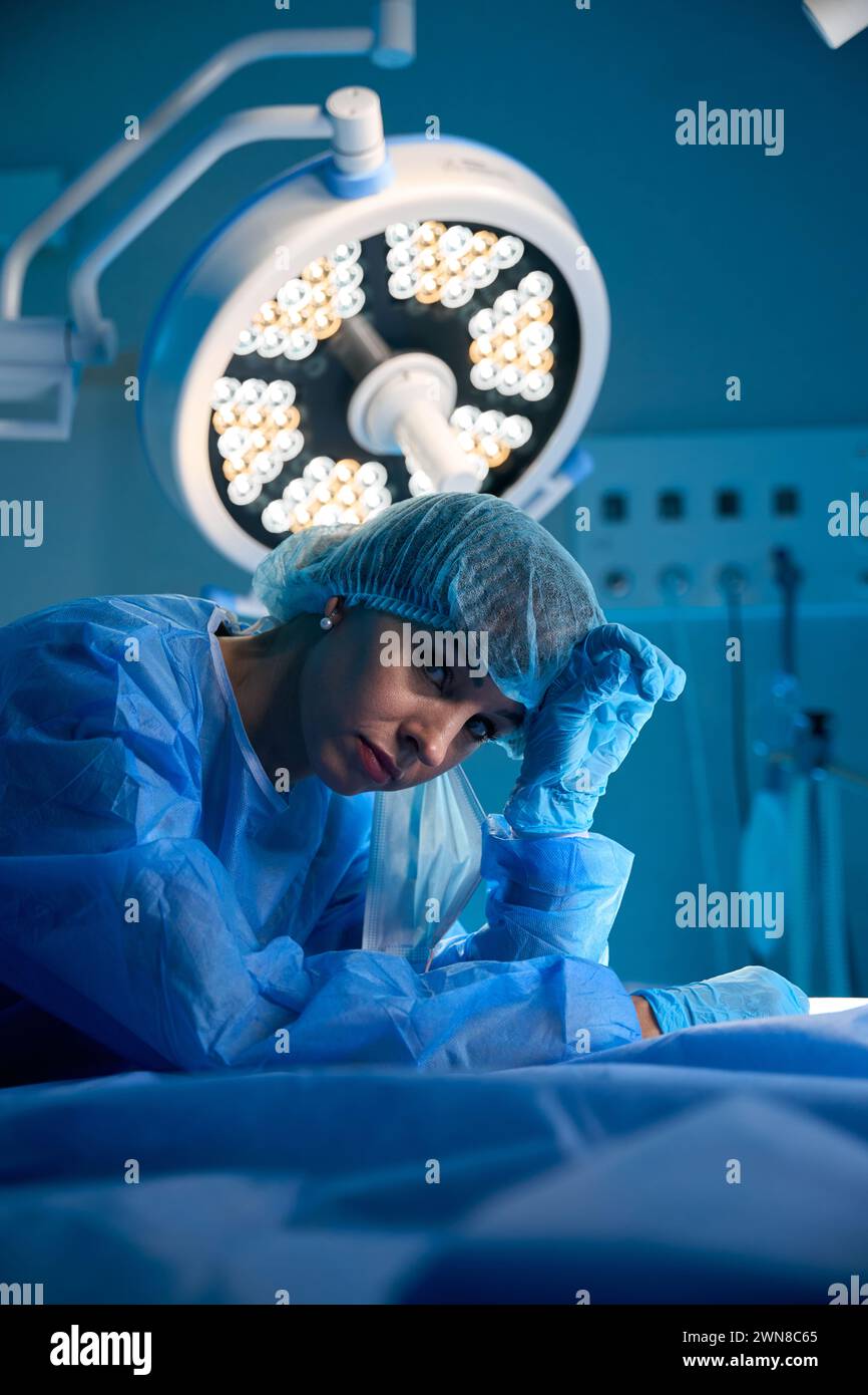 Tired woman surgeon in operating room after major surgery feeling ...