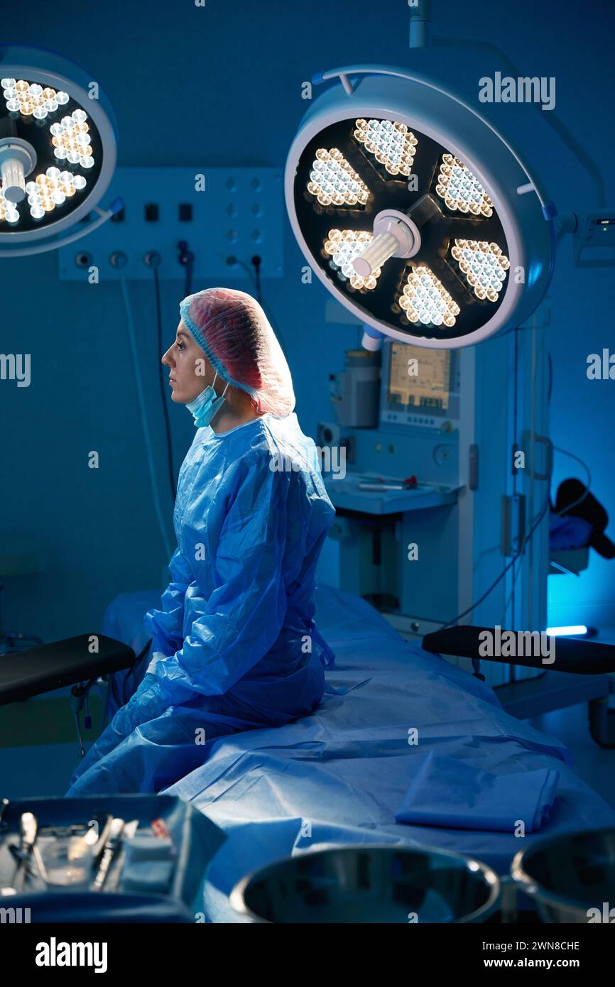 Woman surgeon sitting on operating table in operating room after ...