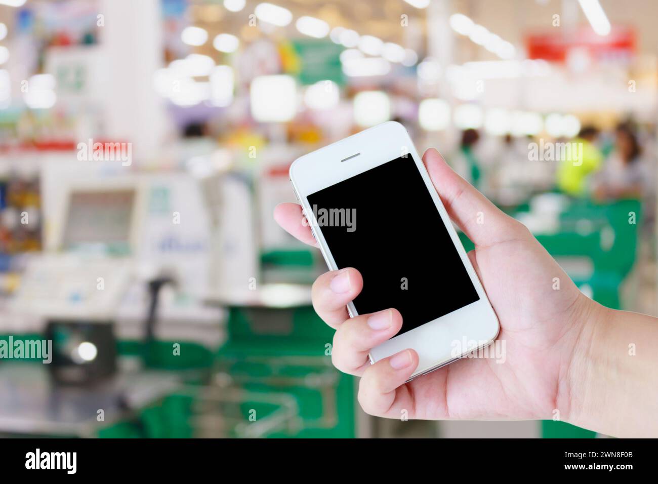 Hand holding mobile phone at supermarket checkout background, digital ...