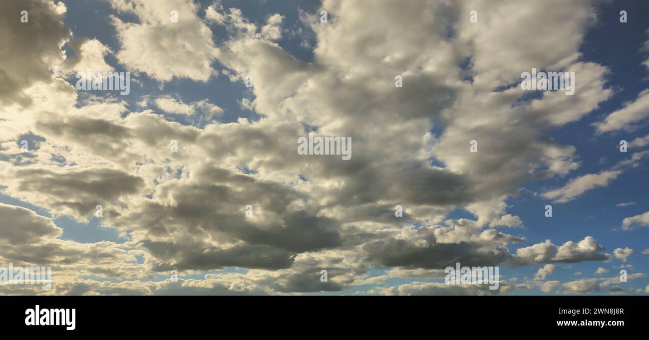 A blue cloudy sky with many small clouds blocking the sun Stock Photo ...