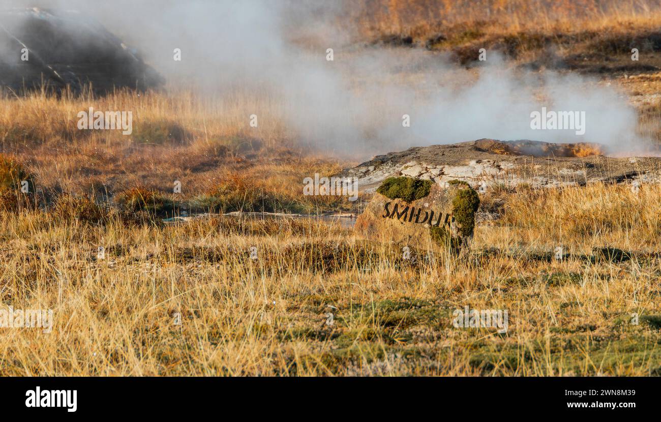 Still water geyser front surrounded with rocky terrain and dry green ...
