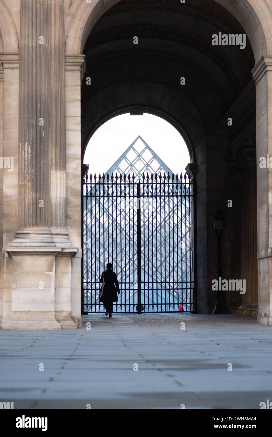 A woman walking towards the metal gates of the Louvre Museum Stock ...
