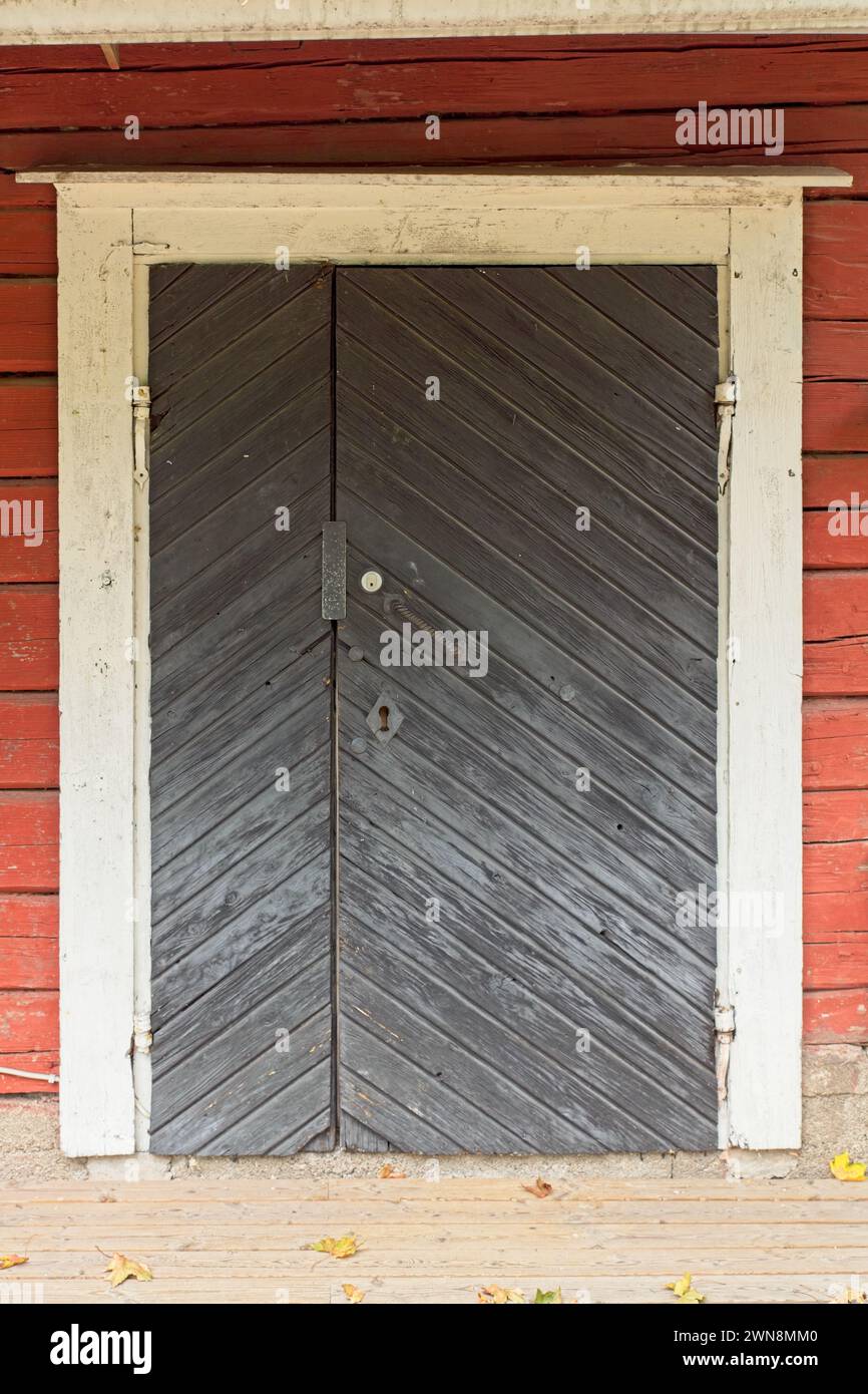 Black door with white frames on a old red painted wooden building Stock ...