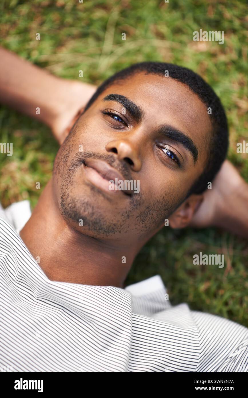Black man, relax and lying on grass while resting, sleeping and enjoy ...