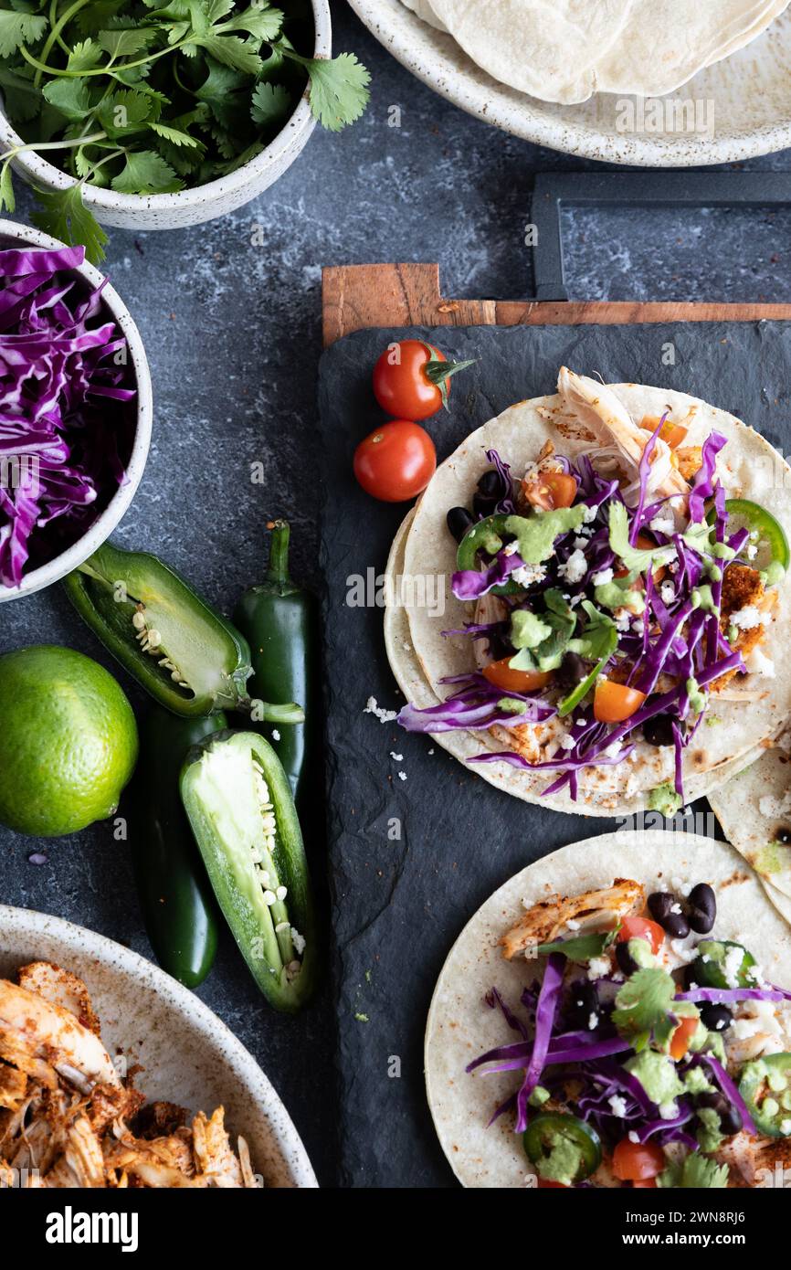 overhead of tacos on dark stone background with colorful ingredients ...
