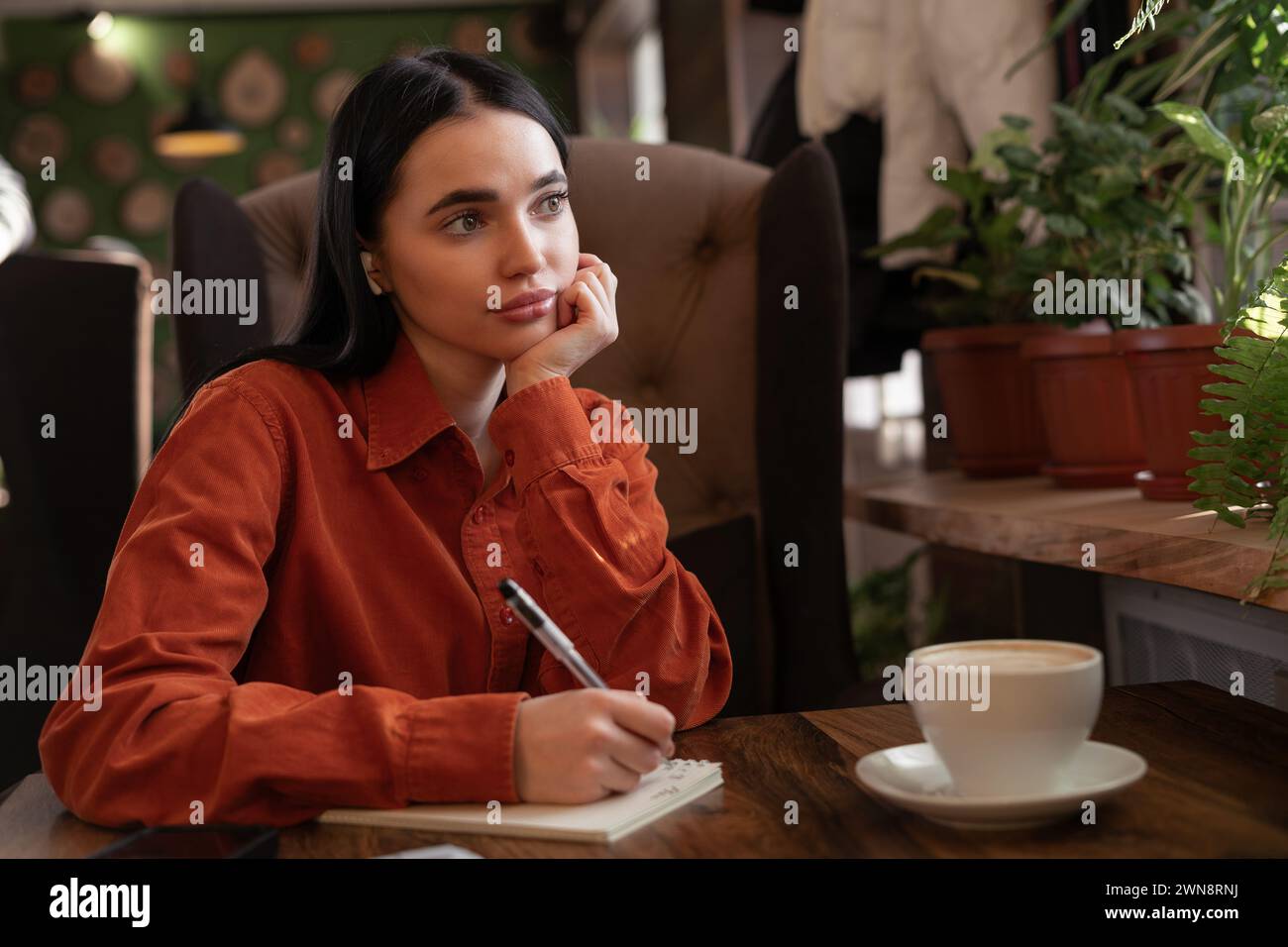 Cute thoughtful female writer noting best ideas for magazine article ...