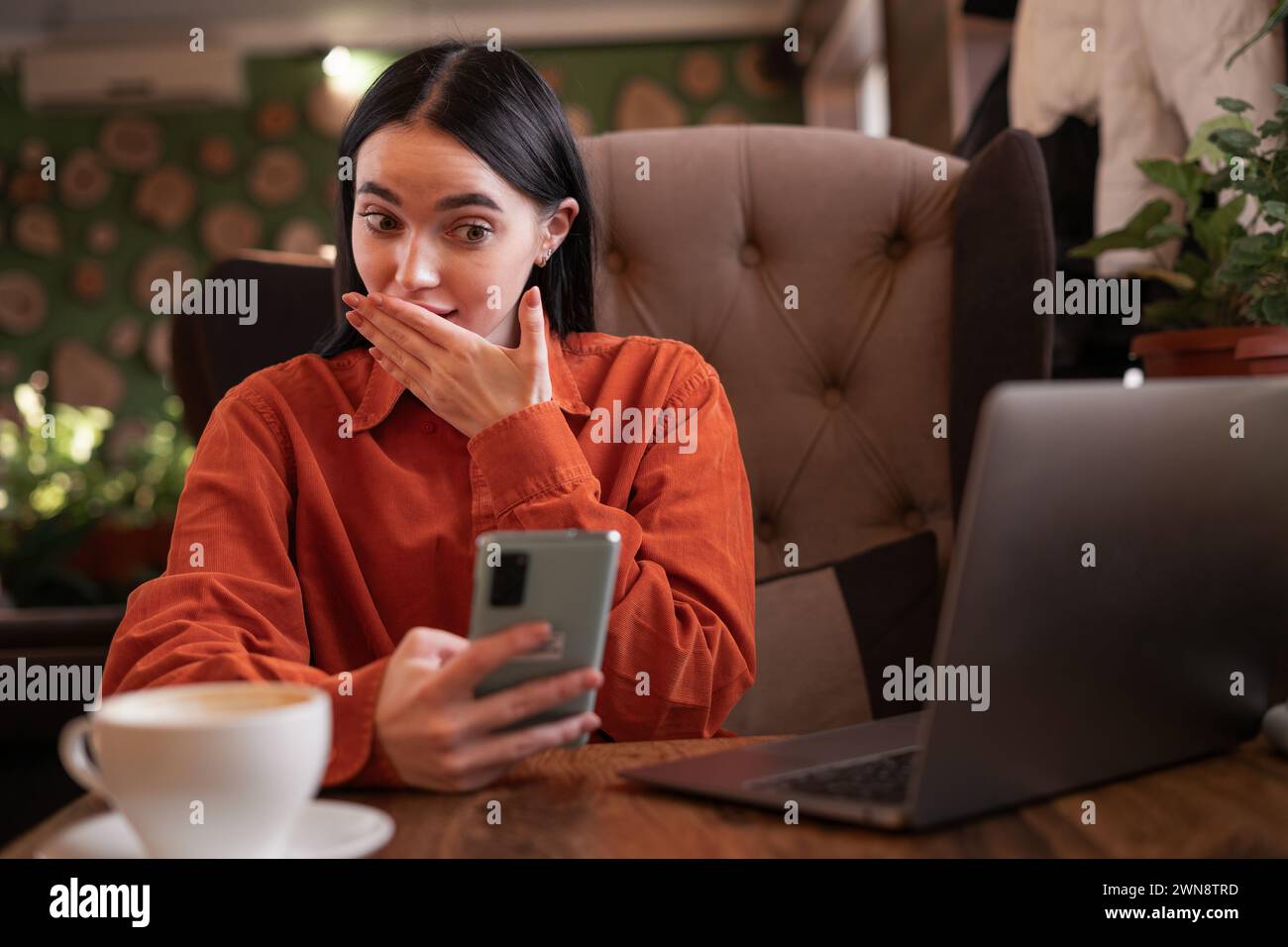 Young shocked anxious woman looking at phone seeing bad news or message ...