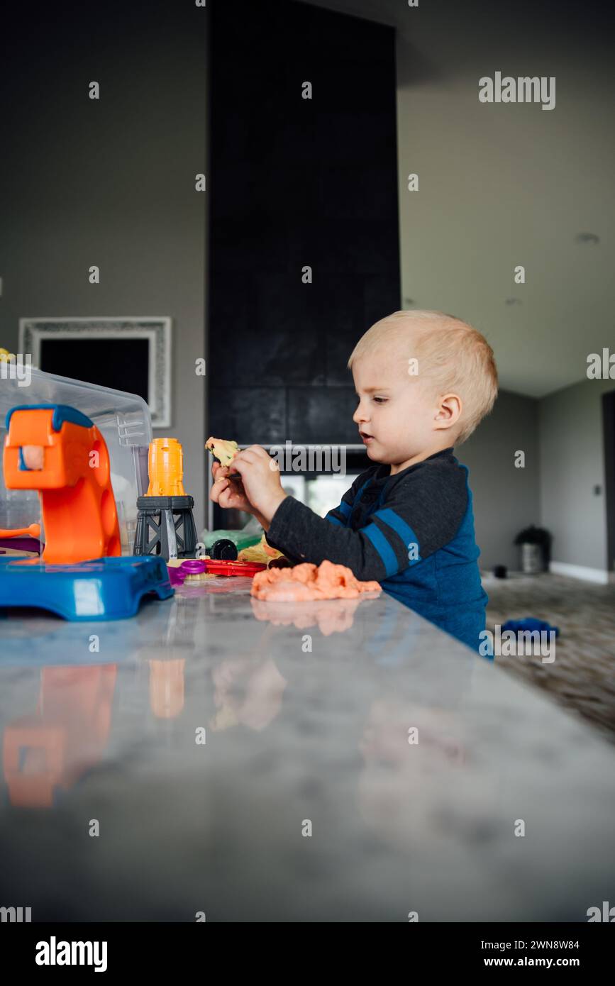 Side view of toddler playing with play doh on counter at home Stock ...