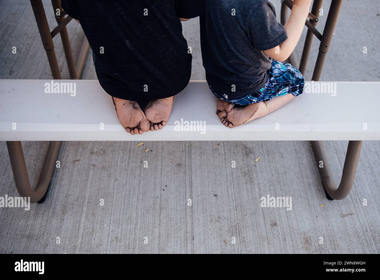 Two children sitting at picnic table with dirty bare feet Stock Photo ...