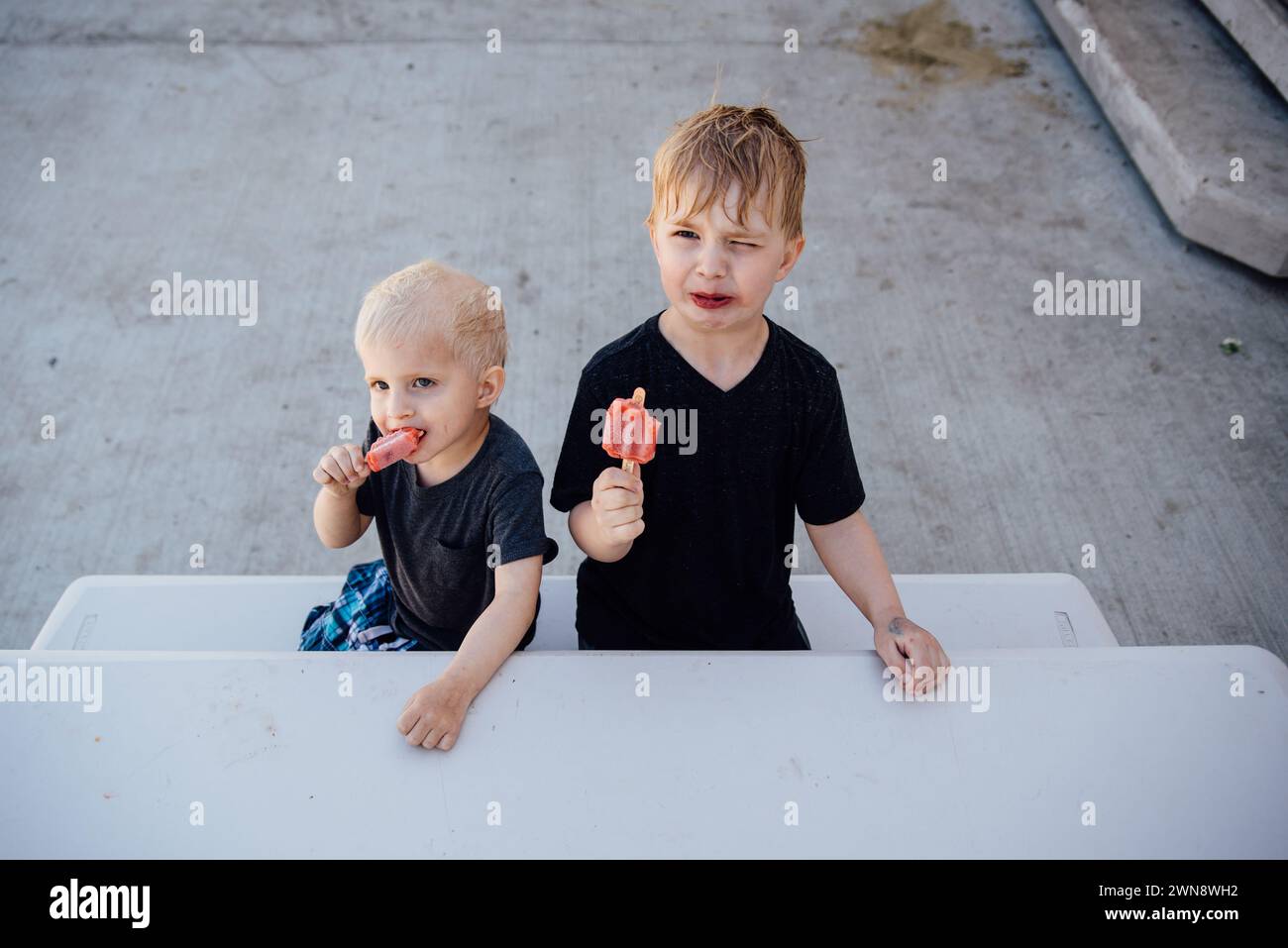 Two boys eating cold popsicles on picnic table in summer Stock Photo ...