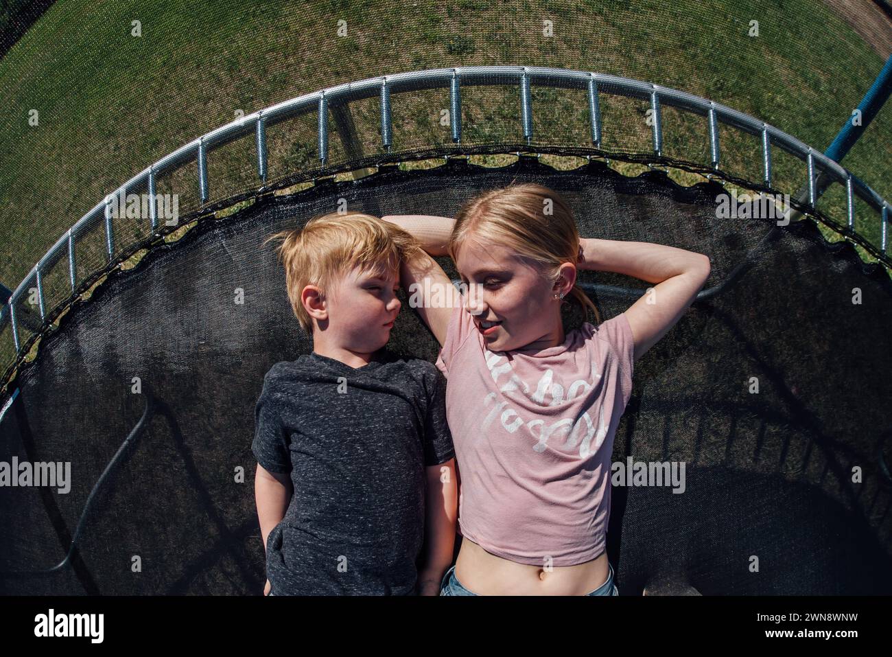 Overhead view of boy and girl talking while laying on trampoline Stock ...