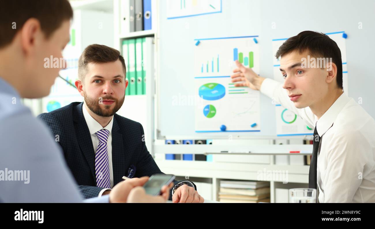 Bunch of businessmen sitting in office solving current problems Stock ...