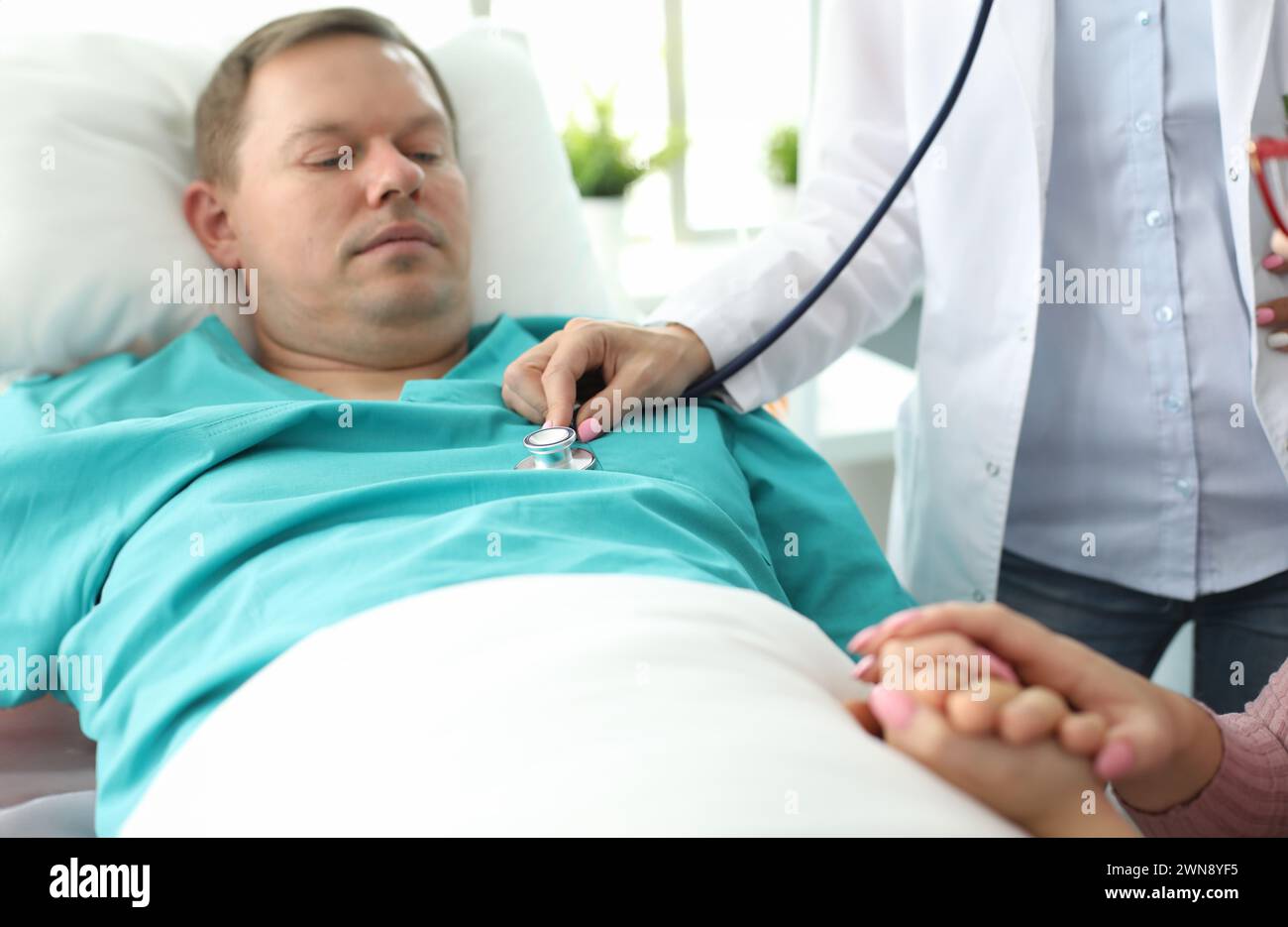 Sick man lies on bed in clinic, doctor examines Stock Photo - Alamy