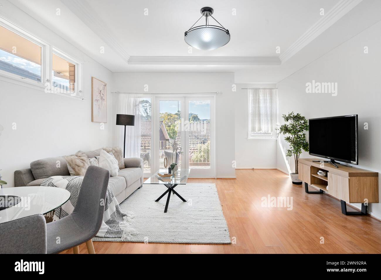 A white living room with wooden flooring and a modern flat screen ...