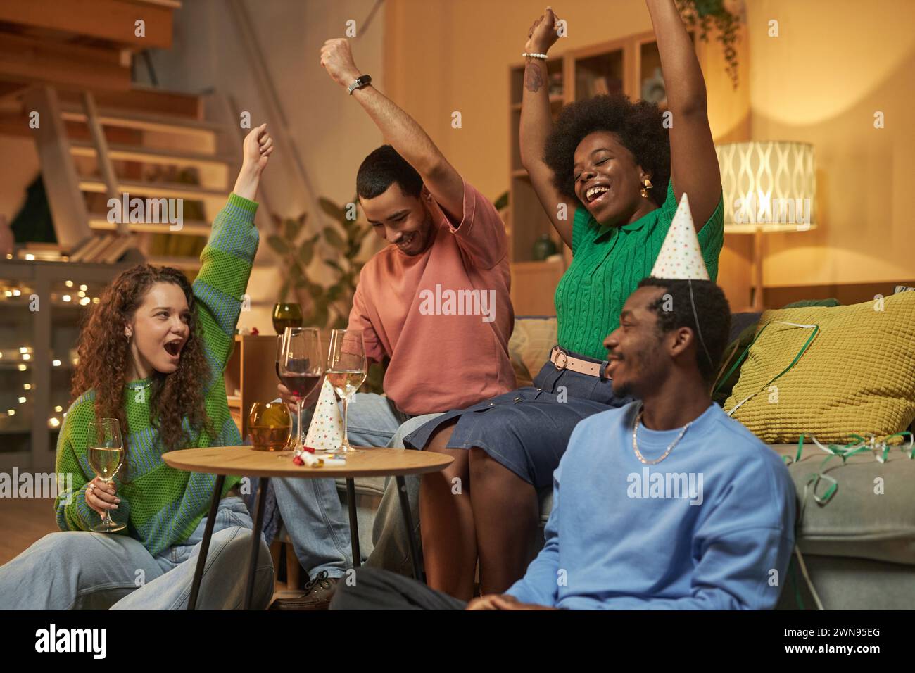 Portrait of multiethnic young people cheering happily and raising hands ...