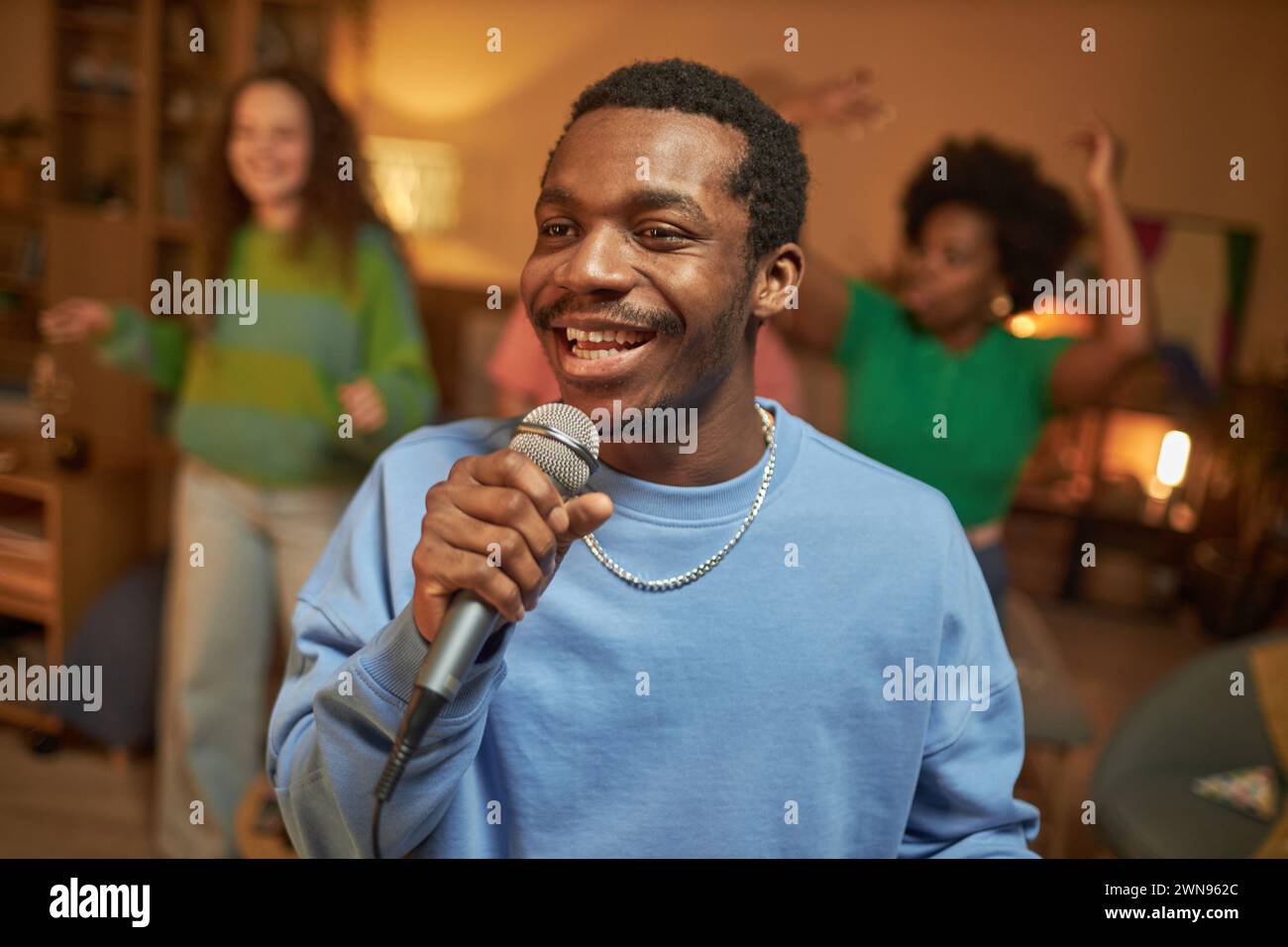 Waist up portrait of Black adult man singing to microphone and smiling ...