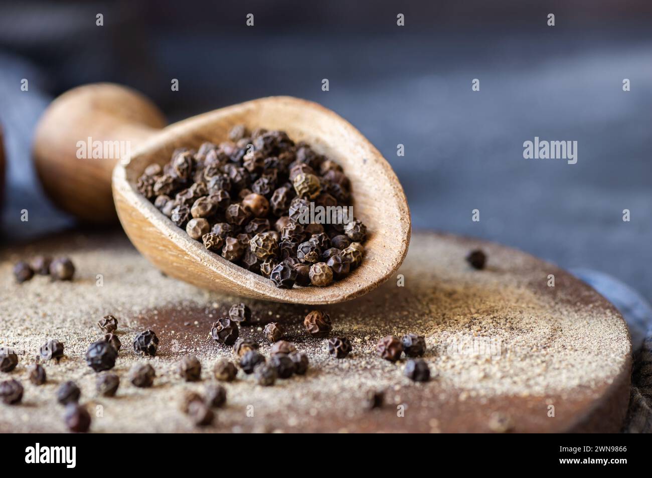 Heap of black pepper, peppercorns in spoon with milled powder on rustic ...