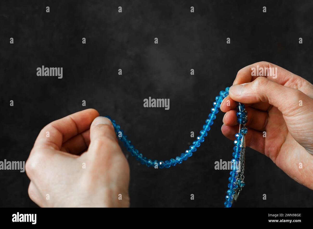 Muslim man praying blue rosary between his hands, worshiping in the ...