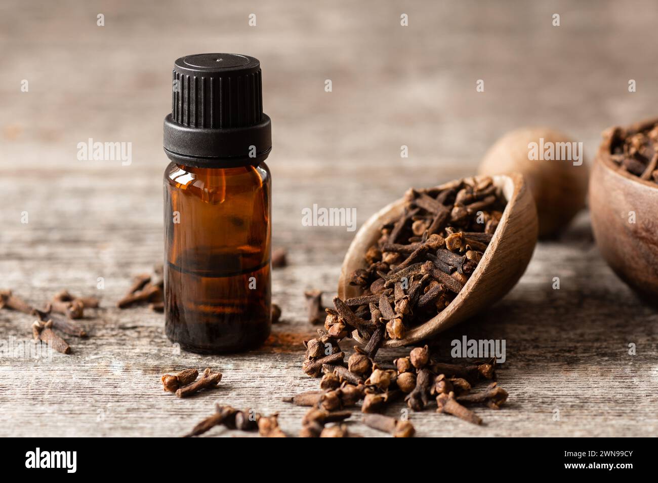 Close up glass bottle of essential clove oil and cloves in wooden ...