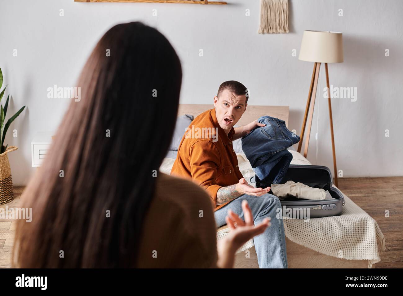 irritated man packing suitcase and quarreling with wife in bedroom at ...