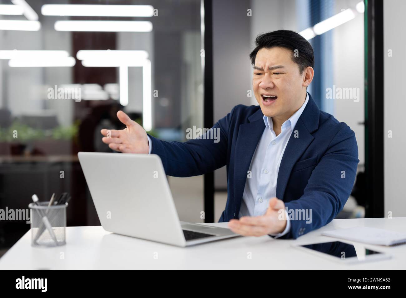 Irritated adult male in business suit spreading arms to portable ...