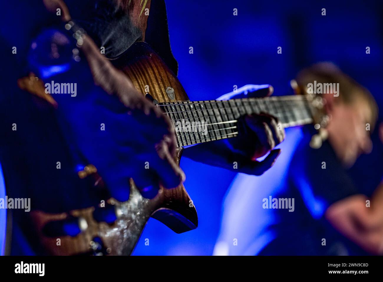 A person plays a guitar at a concert, focus on the hands and the ...