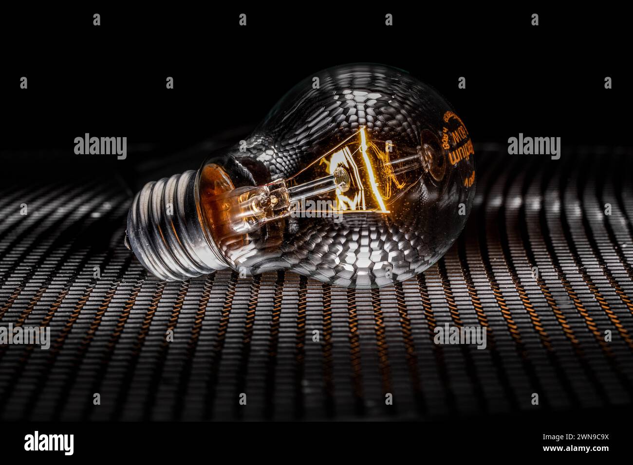 A light bulb on a patterned textile background casts a dramatic shadow ...