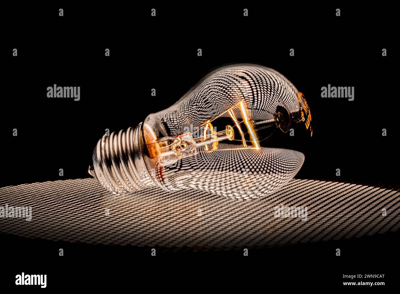 Light bulb lies on a woven surface with an interesting play of shadows ...