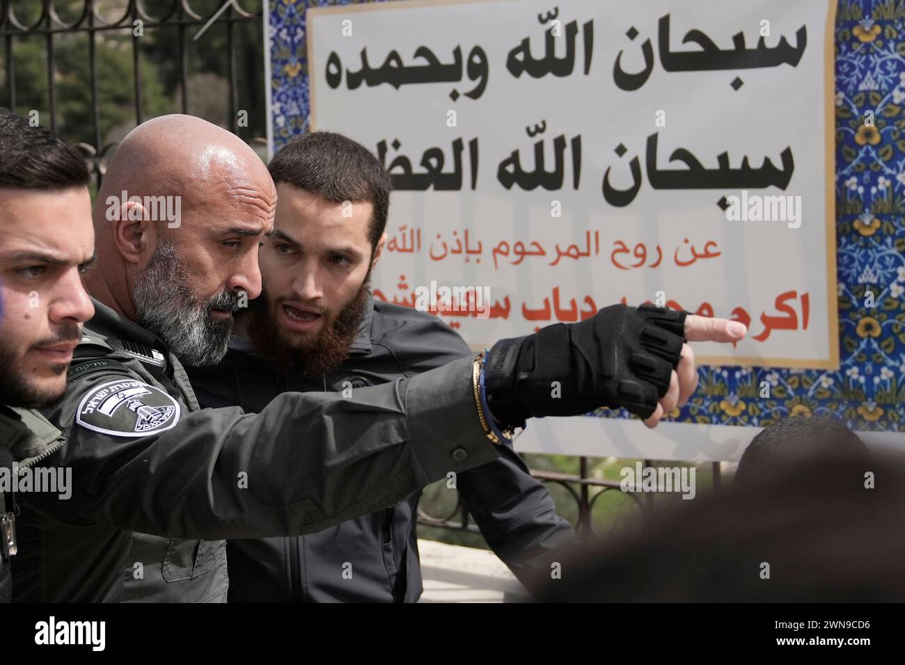 An Israeli Border Police officer directs a Palestinian Muslim man ahead ...