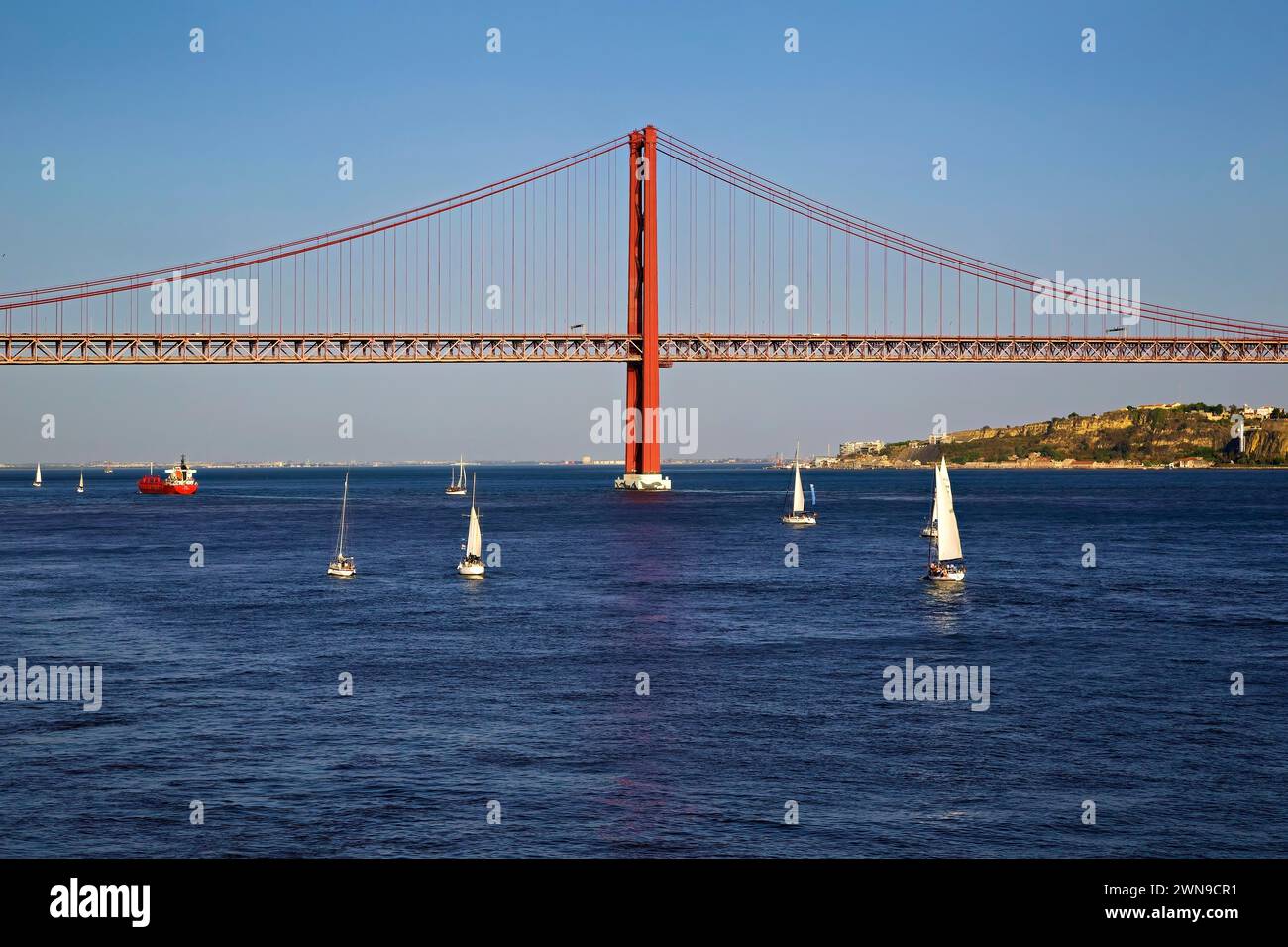 Sailboats glide on the water under the 25 de Abril Bridge in Lisbon ...