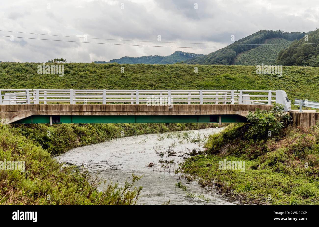 Rural concrete bridge over small stream under cloudy overcast sky in ...
