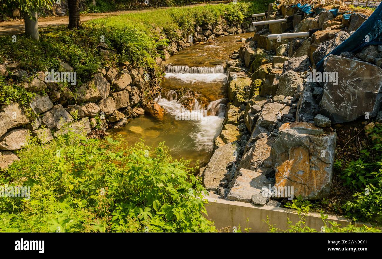 Stream flowing over man made waterfall in rural farming community in ...