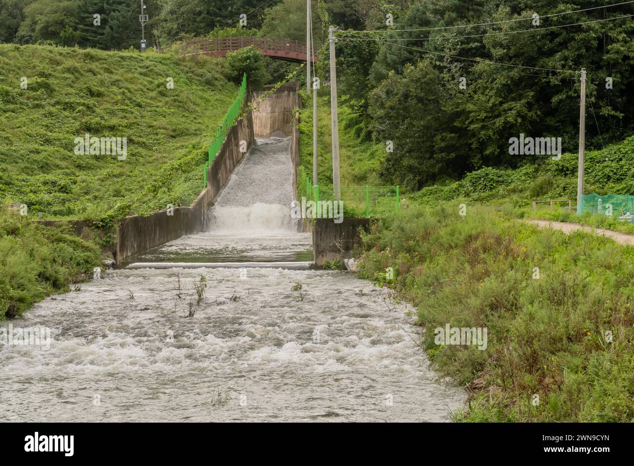 Water flowing rapidly down spillway into small river after torrential ...