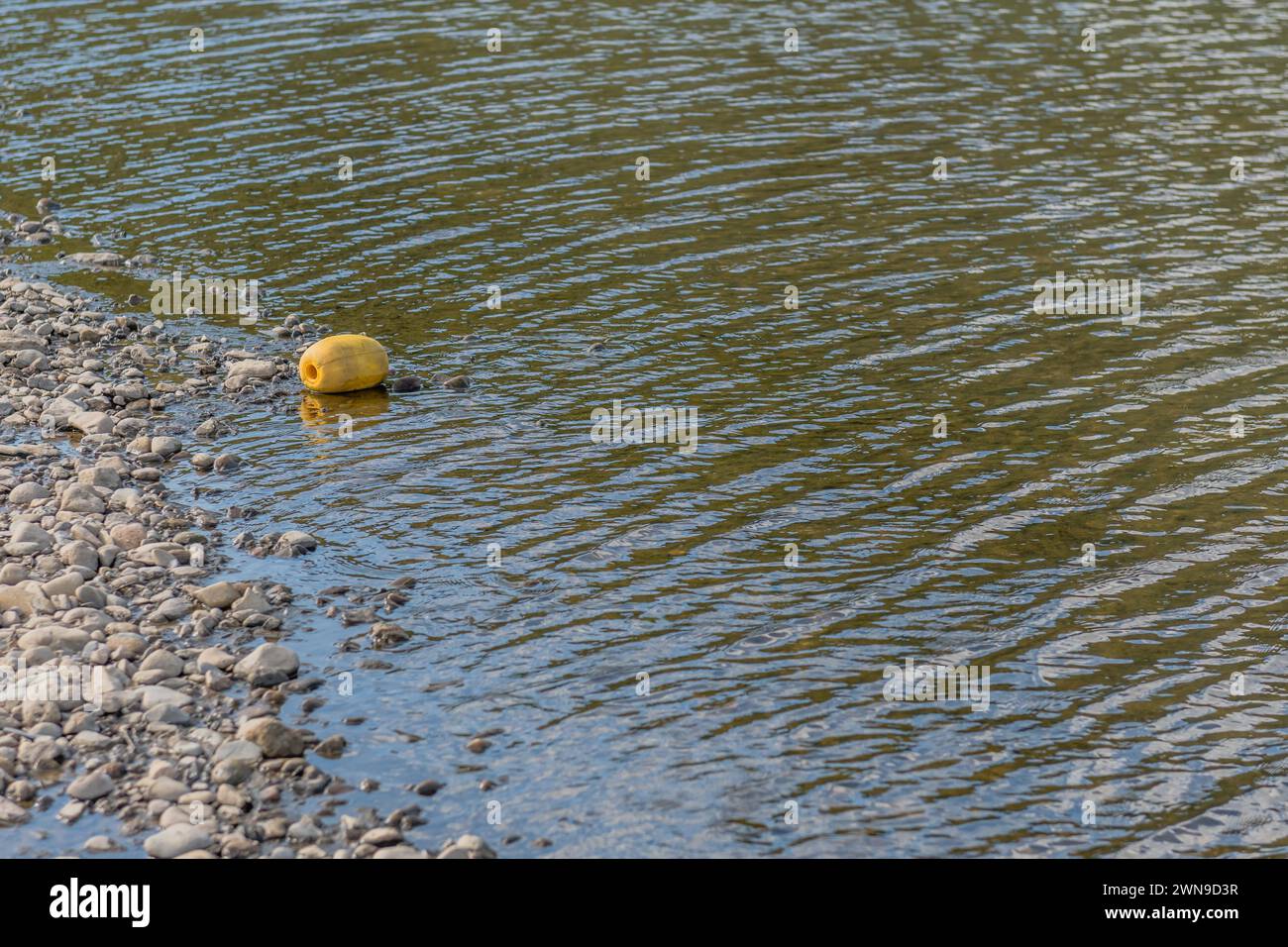 Large yellow Styrofoam buoy in shallow water beside riverbank in South ...